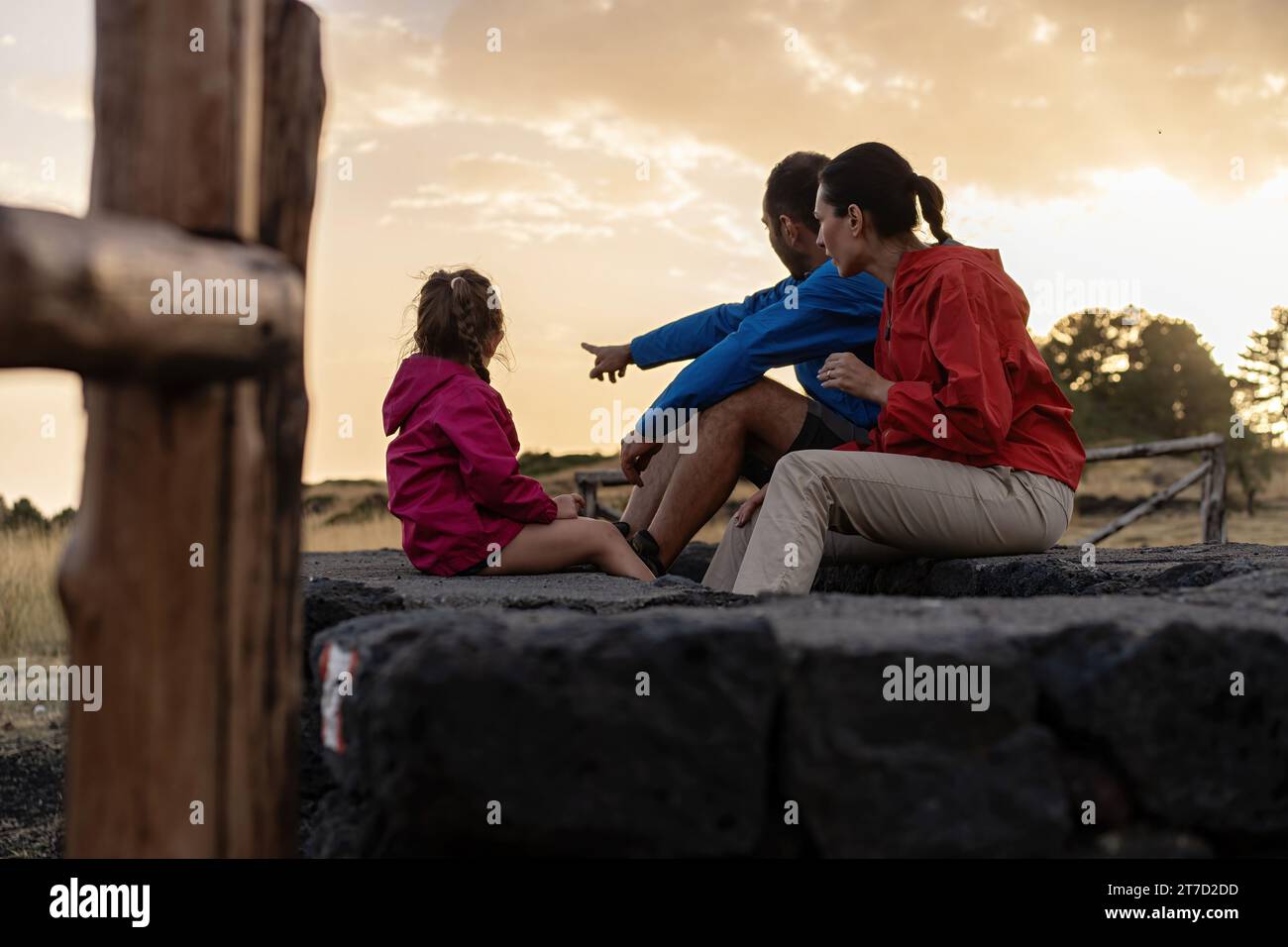 Family sitting together on a nature trail, enjoying a peaceful sunset ...