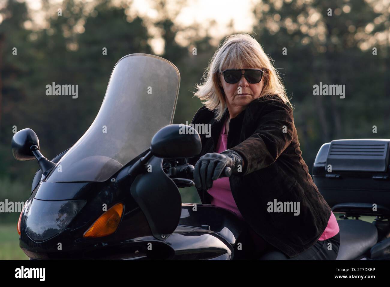 Stylish blonde motorcycle tourist, super mom, grandmother in black ...