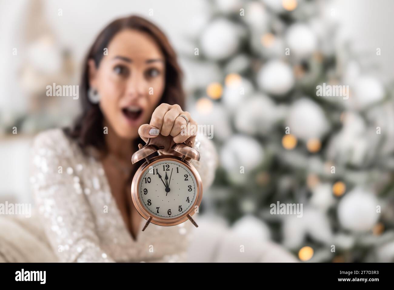 Surprised facial expression of a woman next to a Christmas tree showing ...