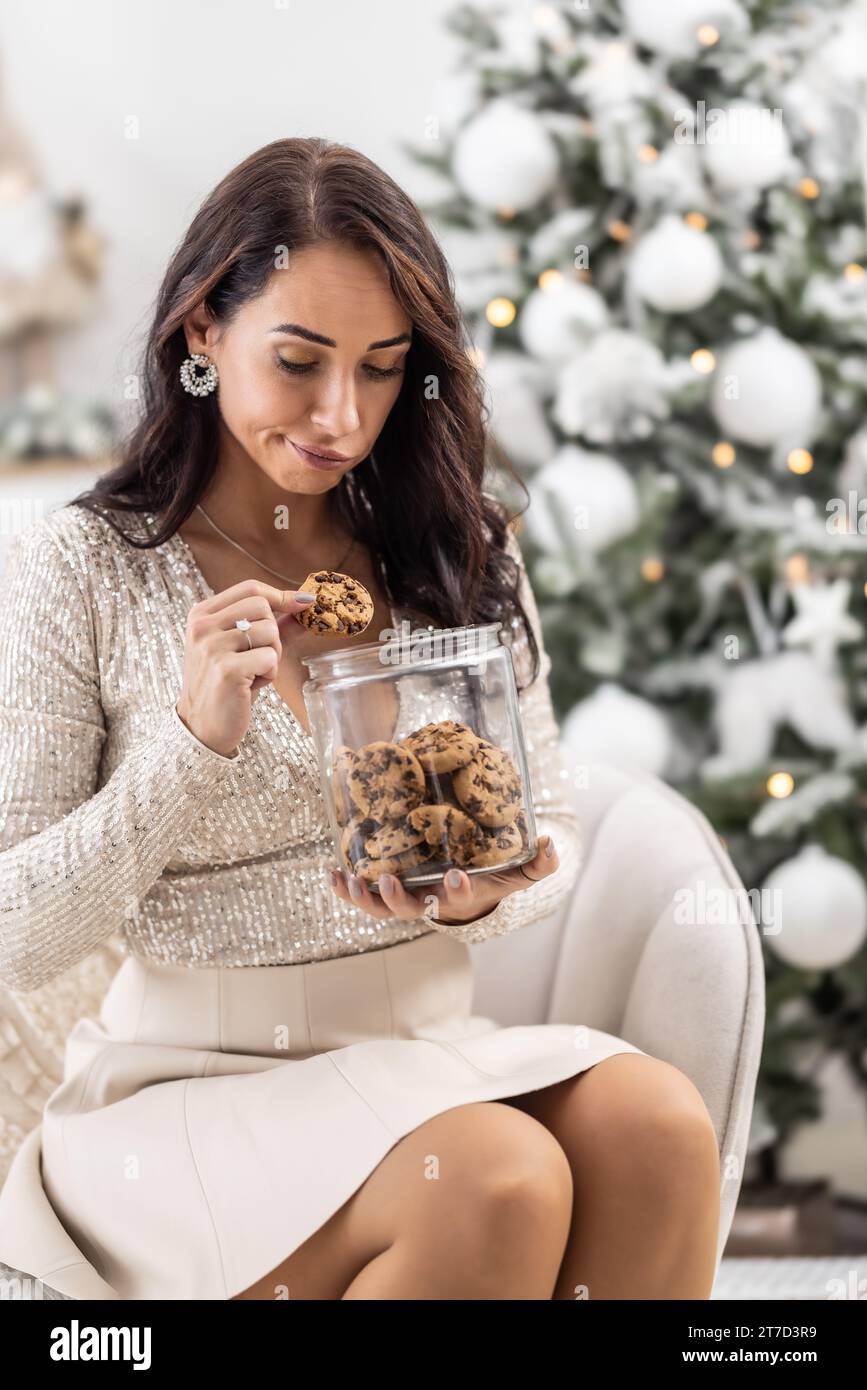 Woman unhappy about irresistible chocolate chip cookies that she takes out of the cookie jar ...