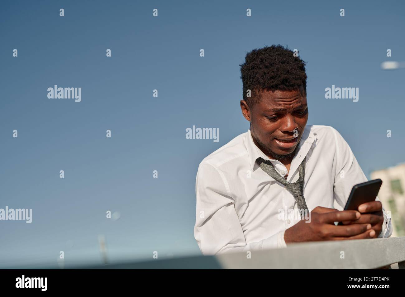 African American man standing outdoors and crying while reading shocked ...