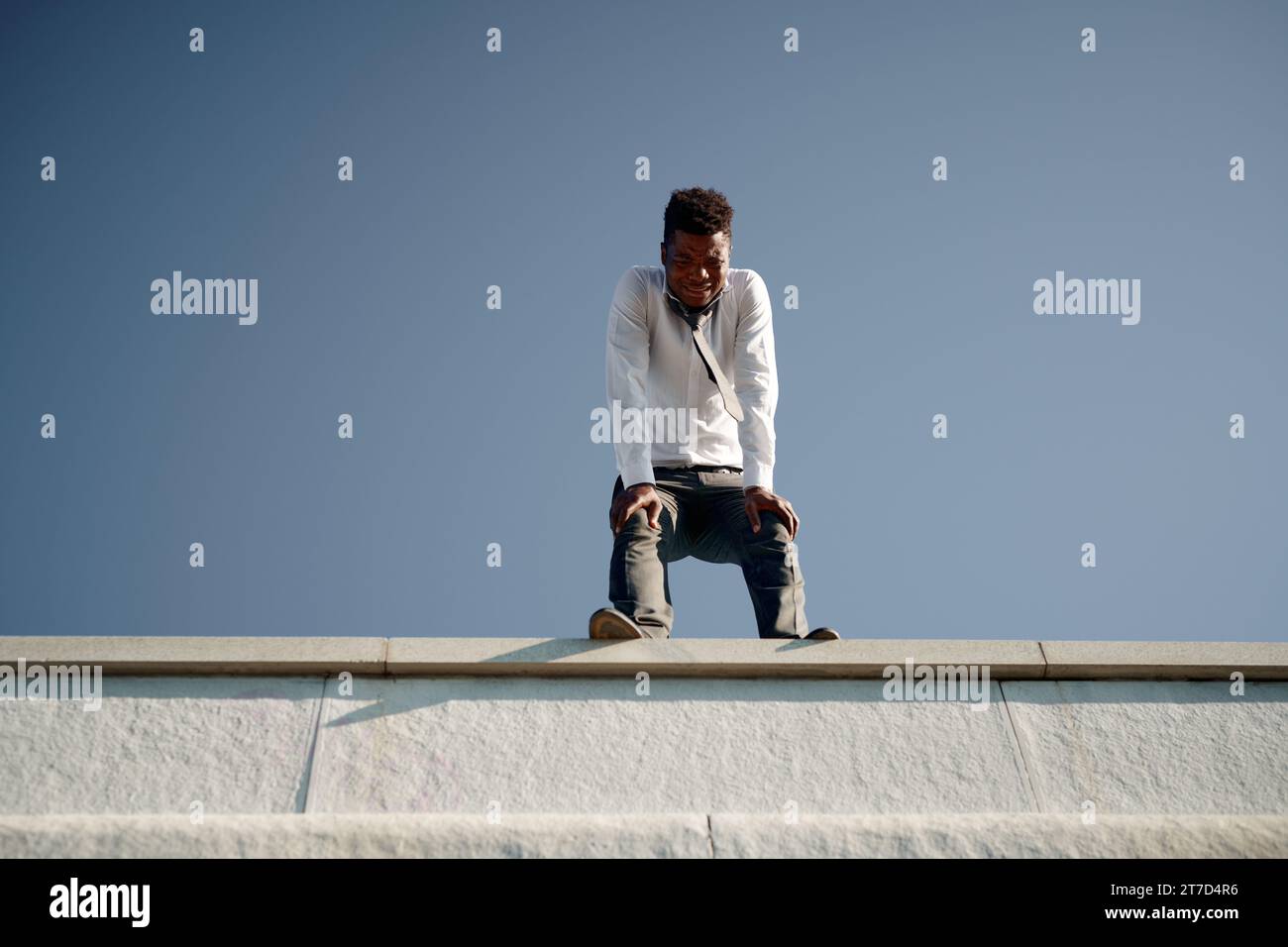 Low angle view of depressed man standing on the edge of the roof and ...