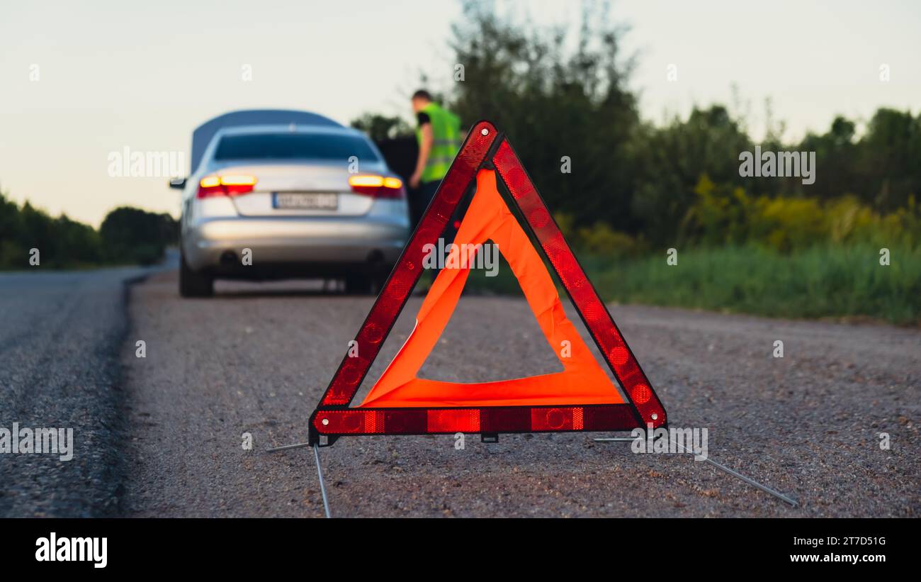 Broken silver luxury car emergency accident. Man driver installing red ...