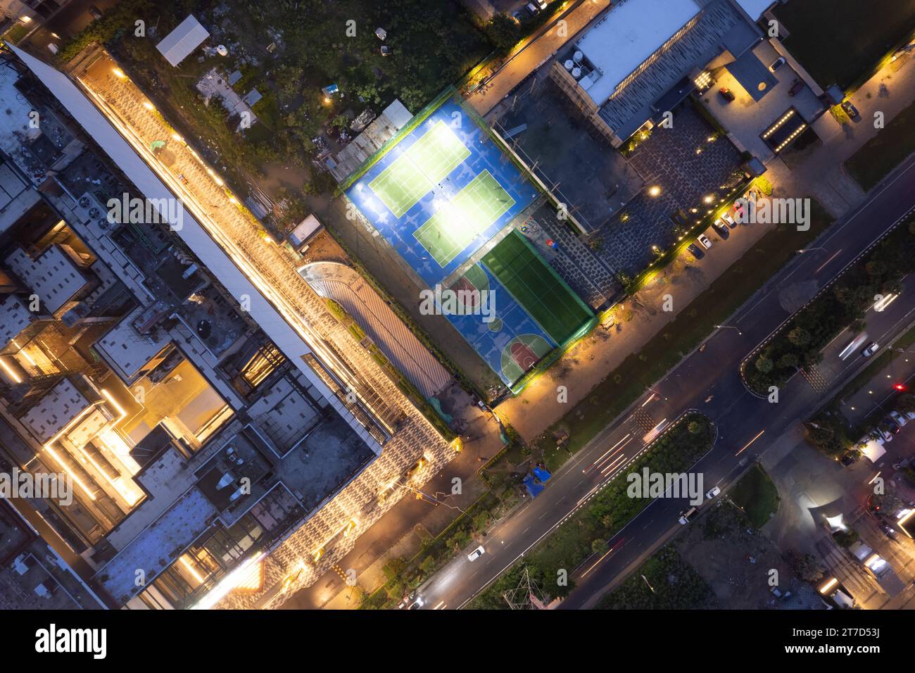 Aerial drone shot showing brightly lit buildings with sports complex ...