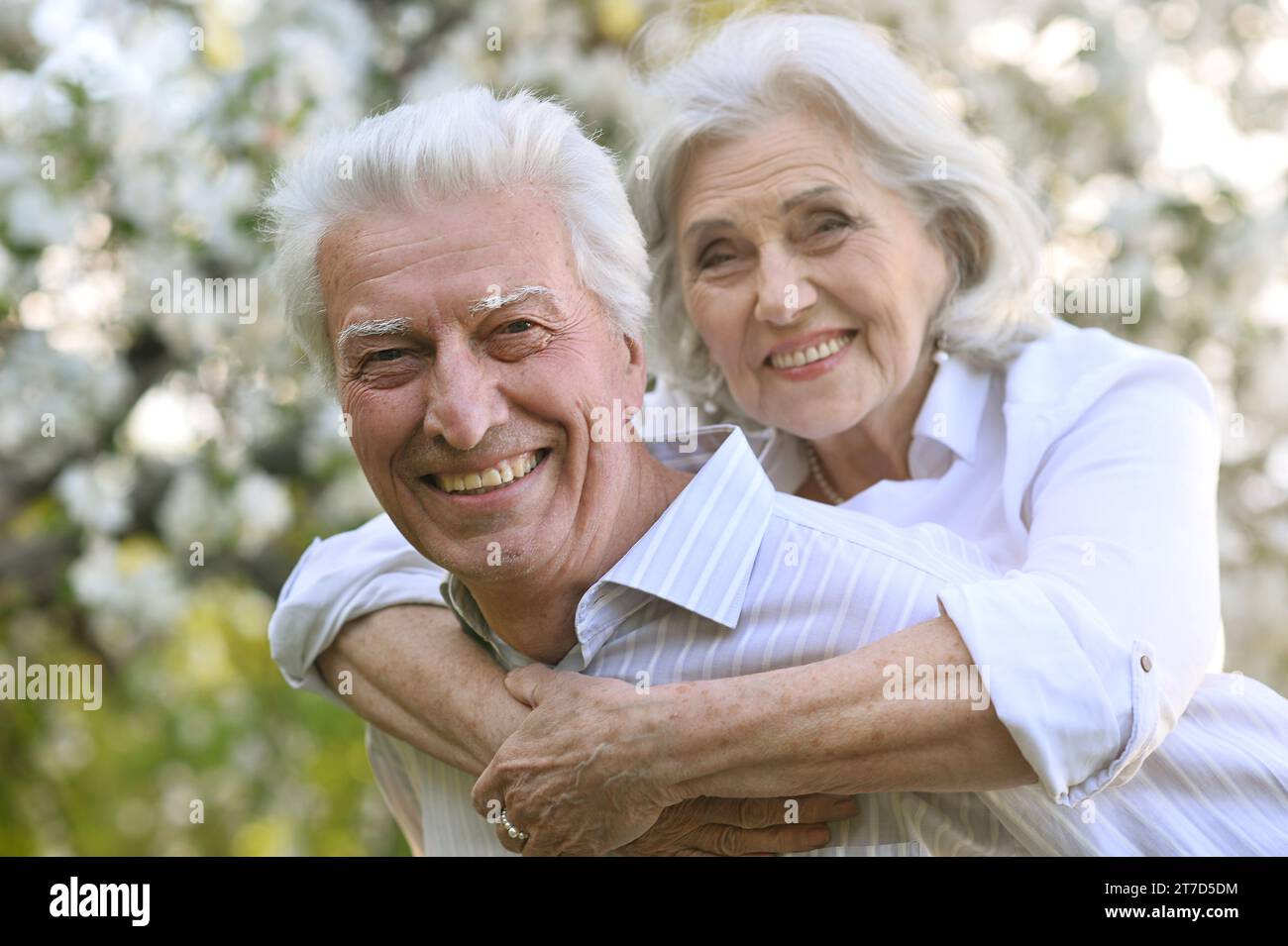 elderly man holding an old woman on his back in nature in summer Stock ...
