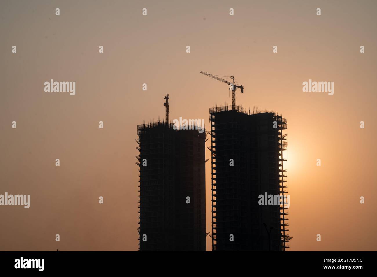 Silhouette of under construction building against sunset with crane on ...