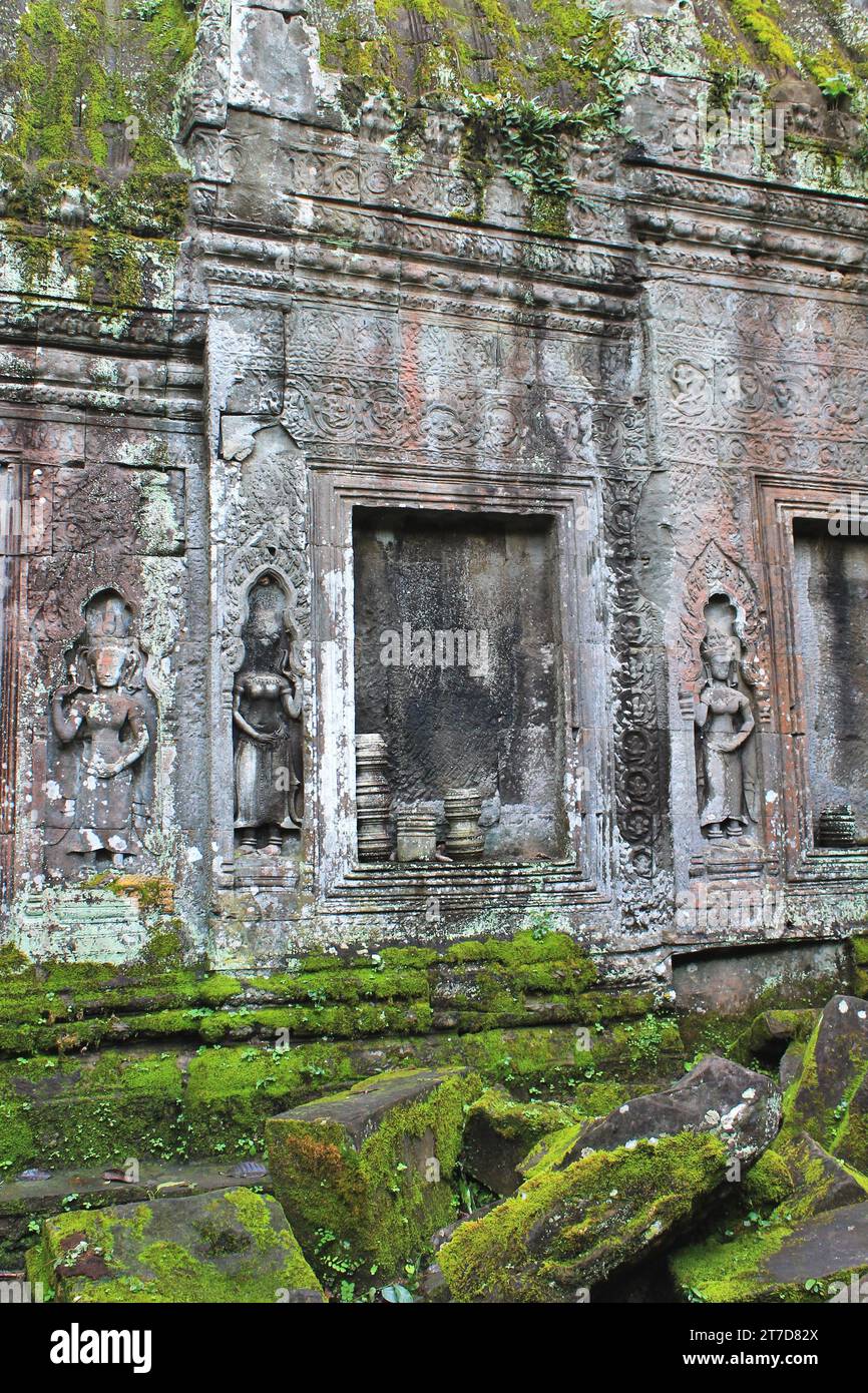 Ancient stone wall at Angkor Wat with carved patterns and female devata ...