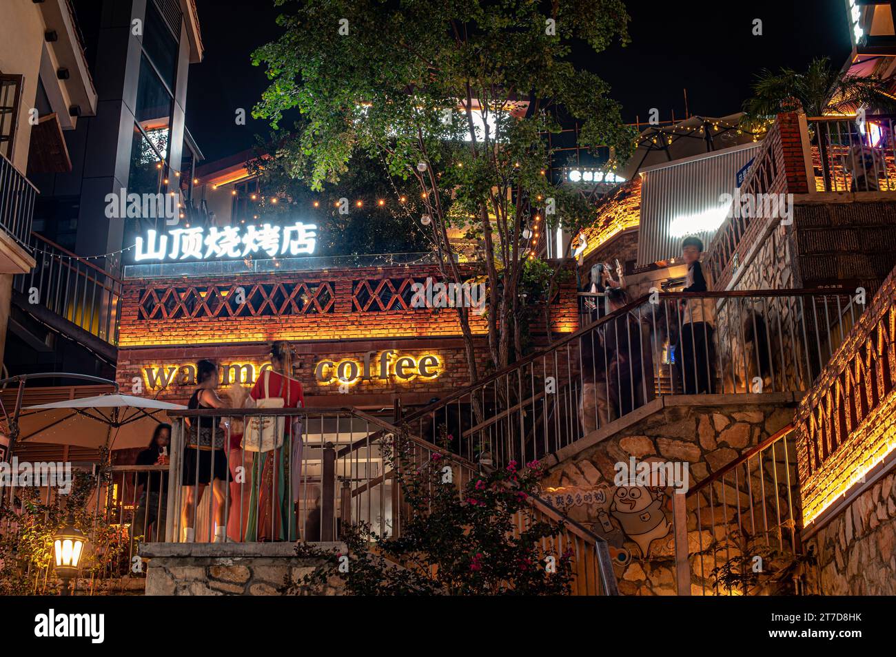 An urban coffee shop illuminated in the night, with a set of stairs ...