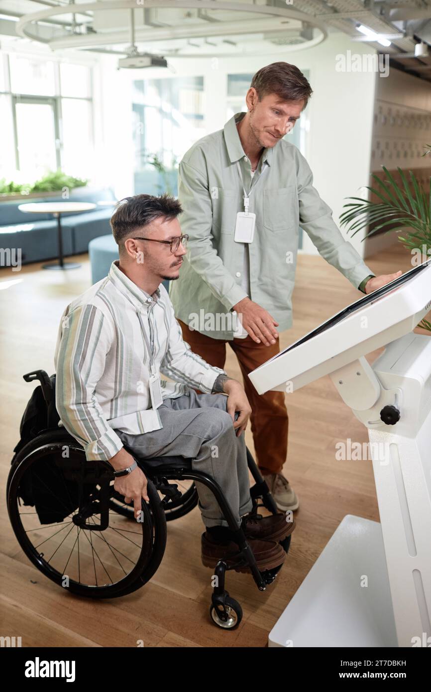 Vertical image of man helping to make online entry for man with ...