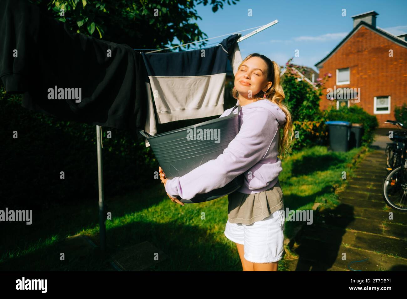 Young caucasian woman hanging clothes on washing line outdoor for ...