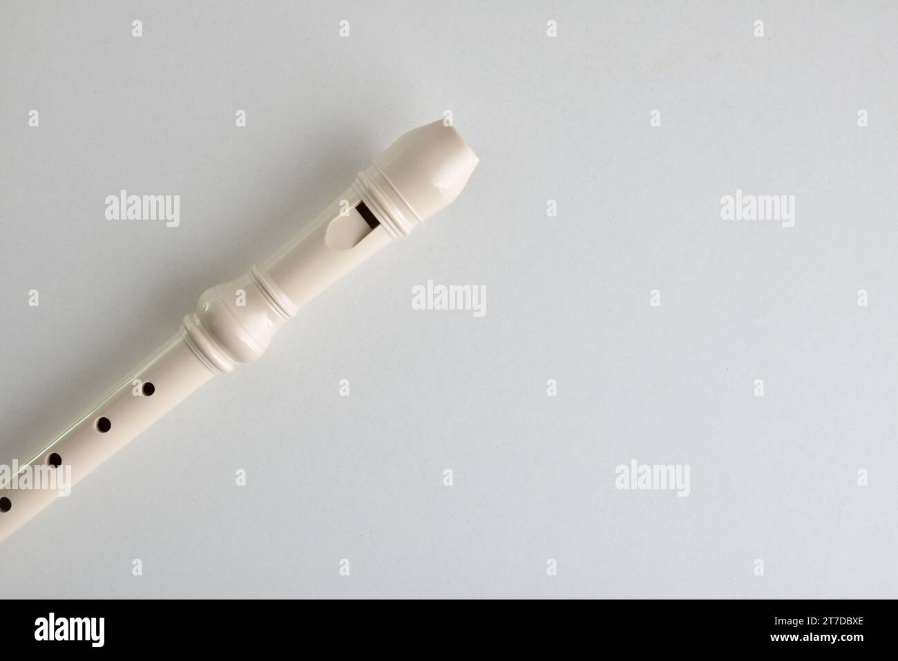 Detail of white plastic recorder on white table in diagonal position ...