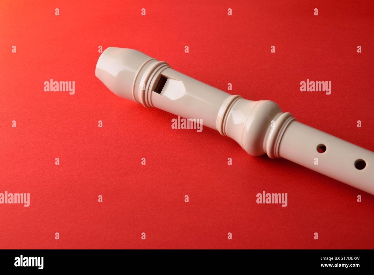 Detail of white plastic recorder mouthpiece on red gradient background ...
