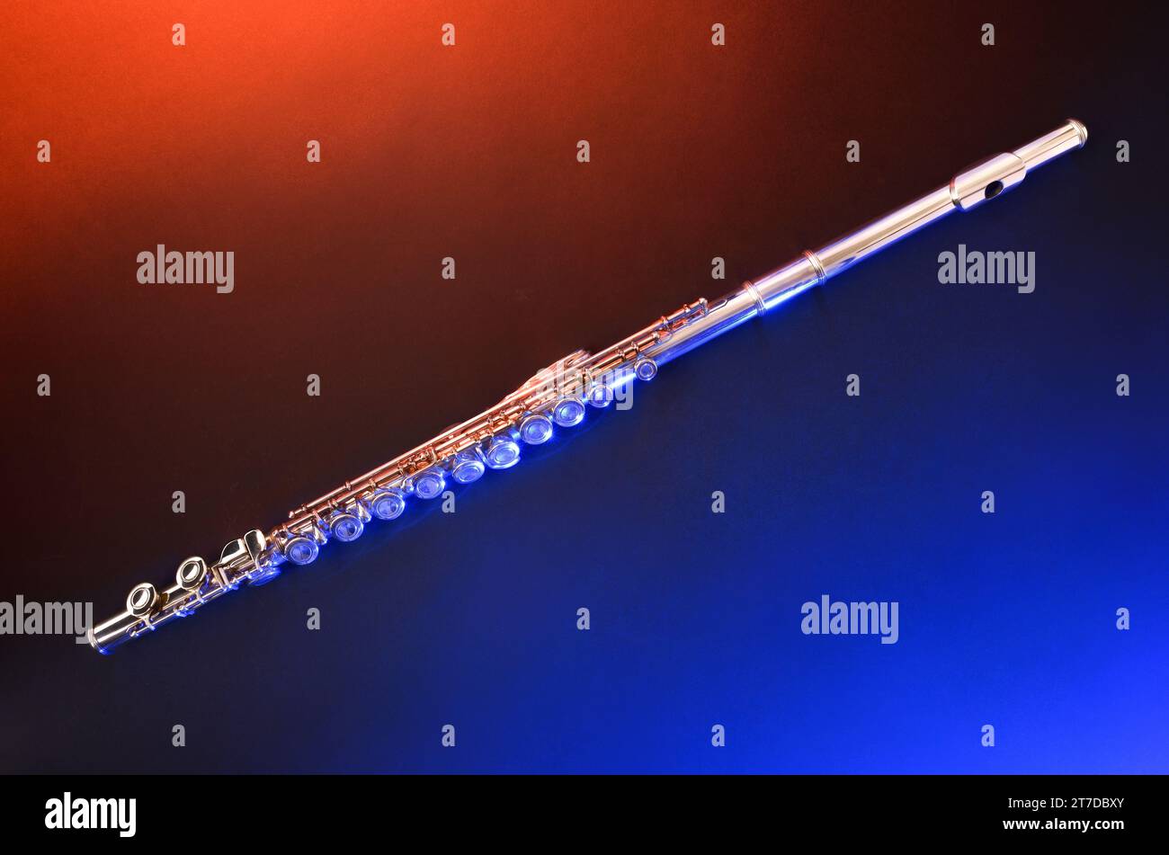 Metal flute on dark table illuminated with red and blue lights ...