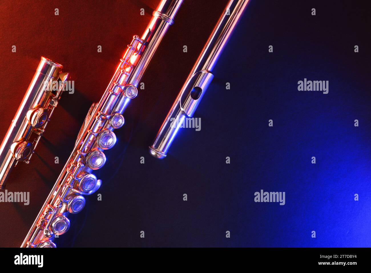 Detail of disassembled metal flute isolated on dark table illuminated ...