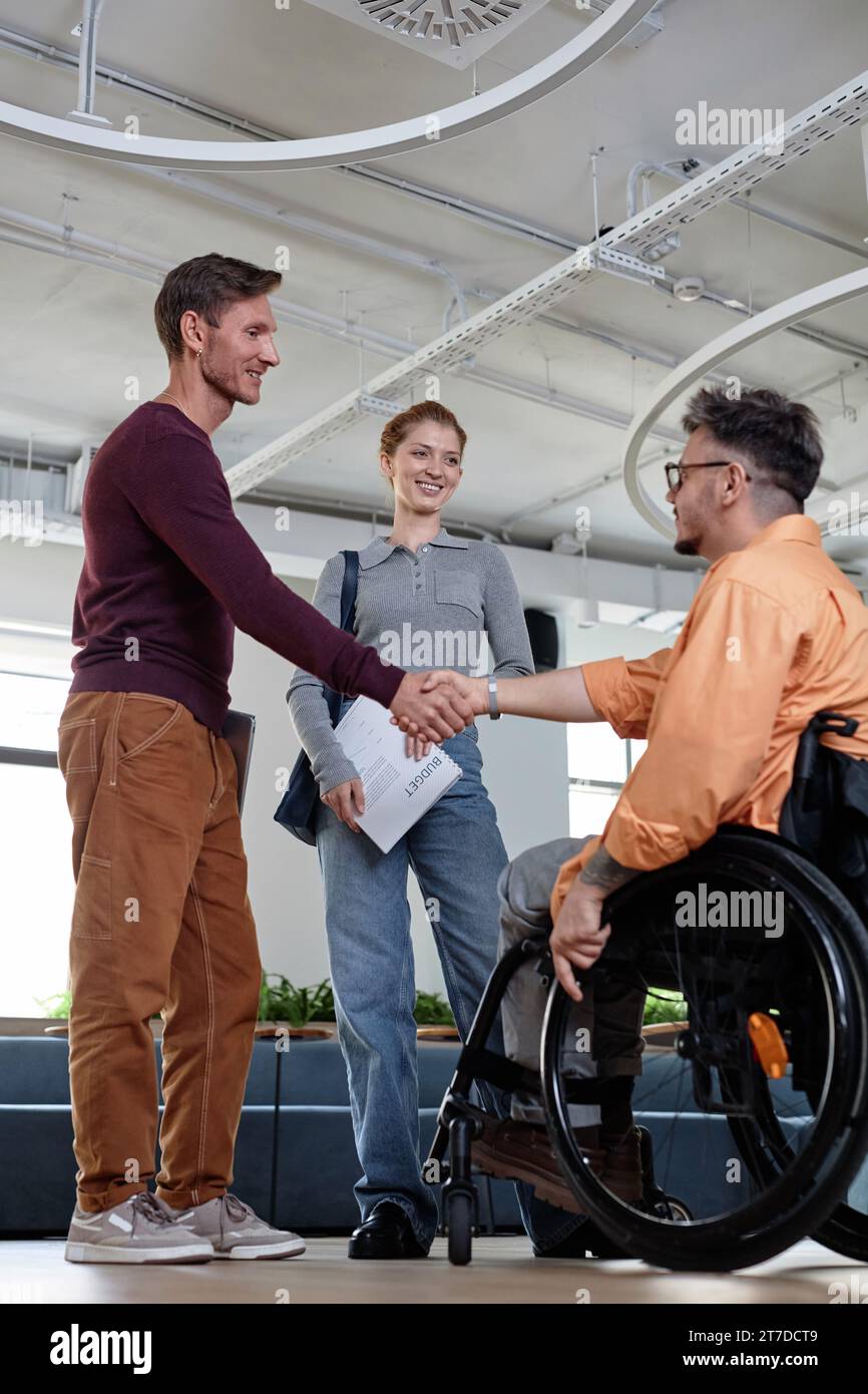 Vertical image of colleagues greeting each other before meeting in ...