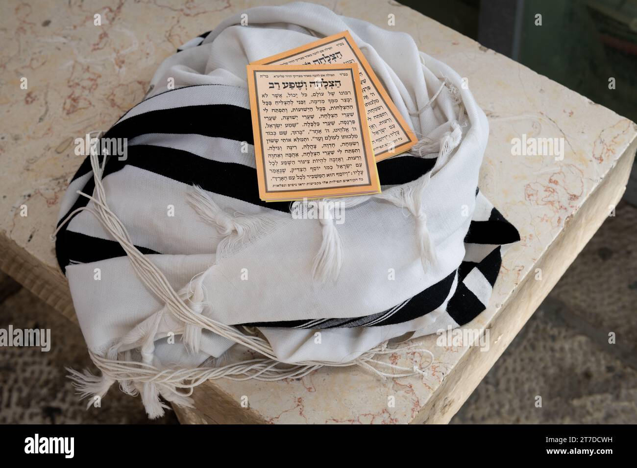 A tallit Jewish prayer shawl folded up on a bench with a booklet ...