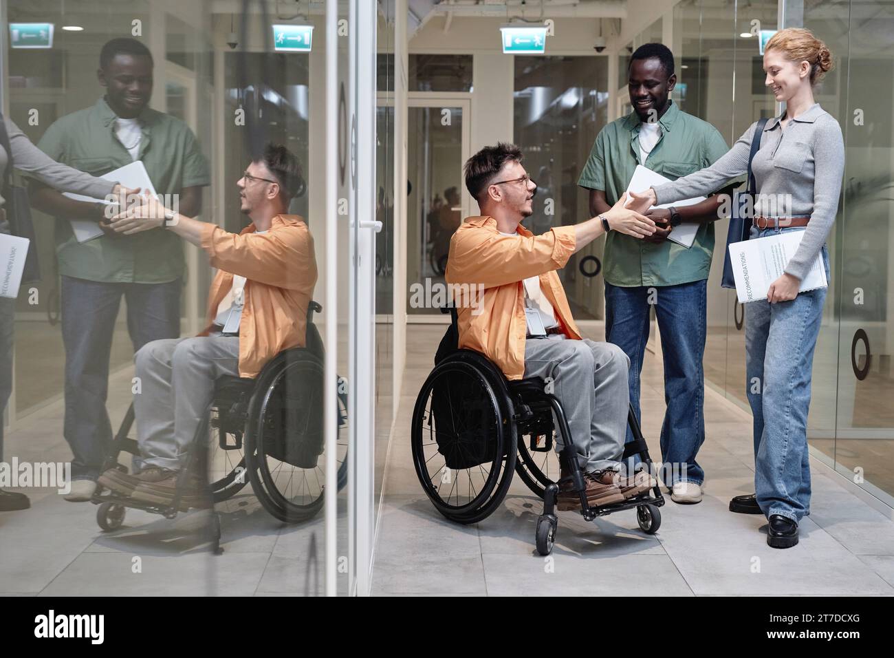 Young colleagues shaking hands and greeting each other in office ...