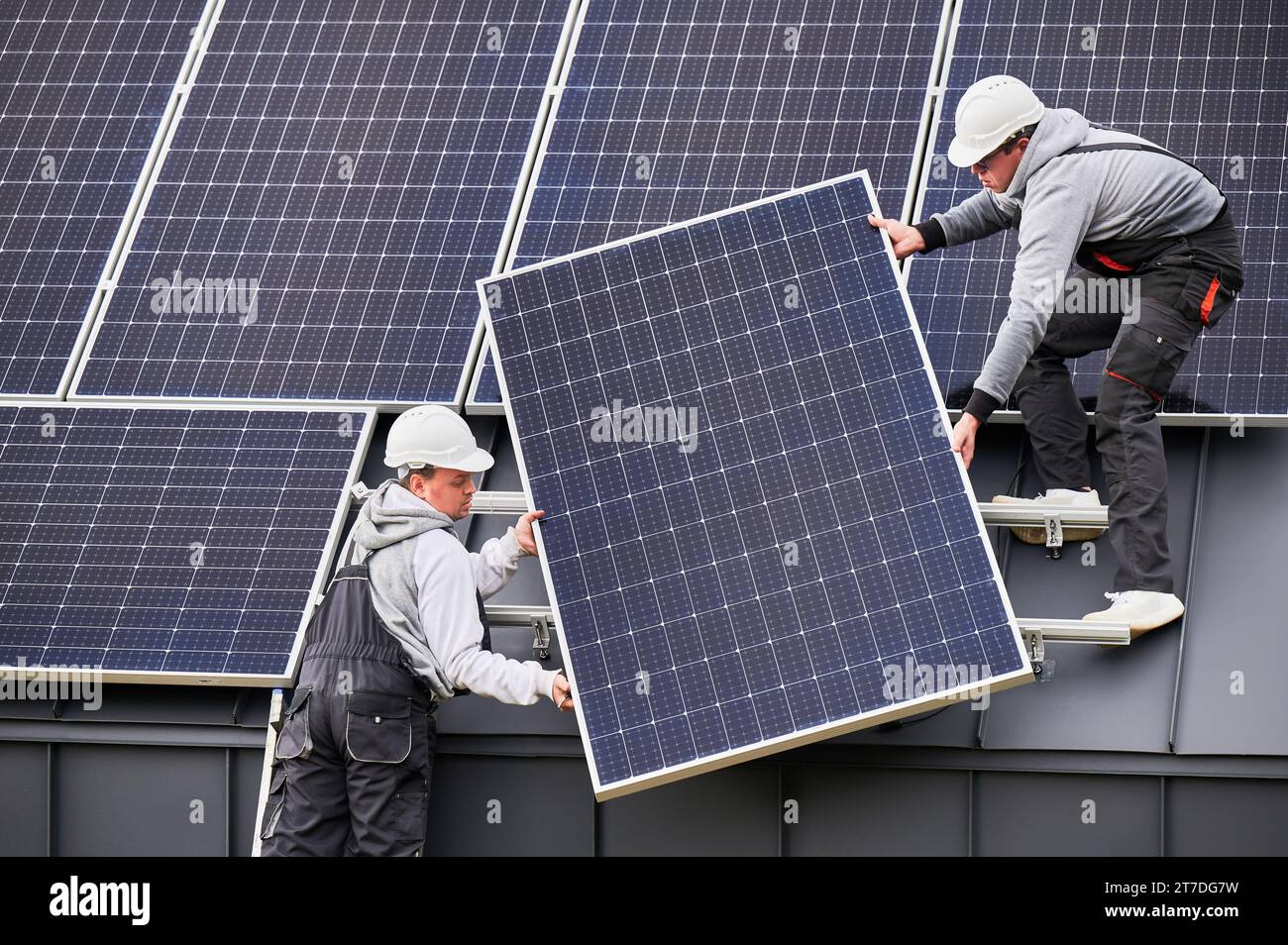 Builders building solar panel system on roof of house. Men workers in ...