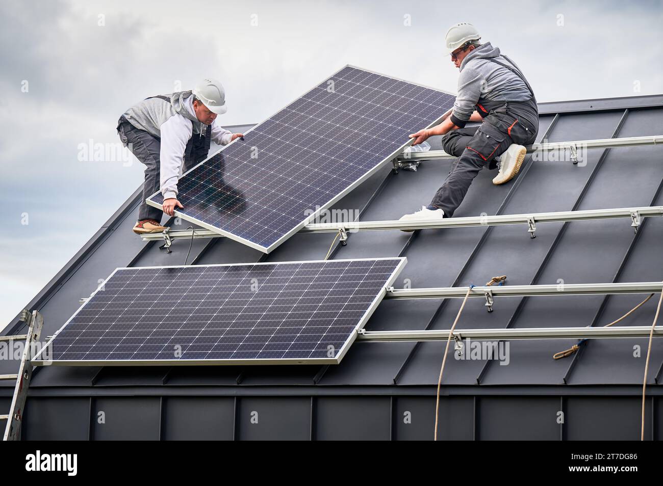 Workers building solar panel system on roof of house. Men technicians ...