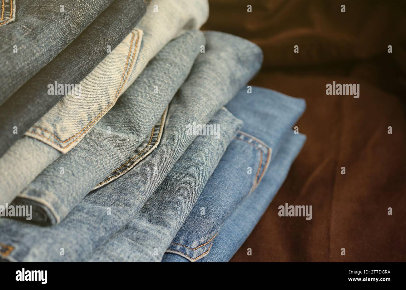 Many jeans in stack in wardrobe room. Row of pants denim jeans in ...
