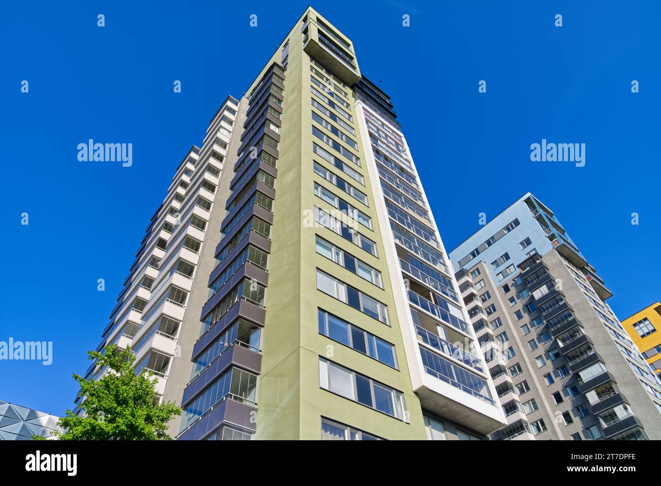 A high-rise building with an abundance of windows and vibrant green ...