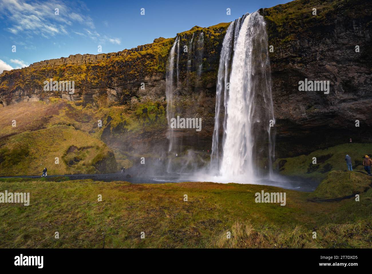 A group of people stand in awe near a majestic waterfall in Iceland ...