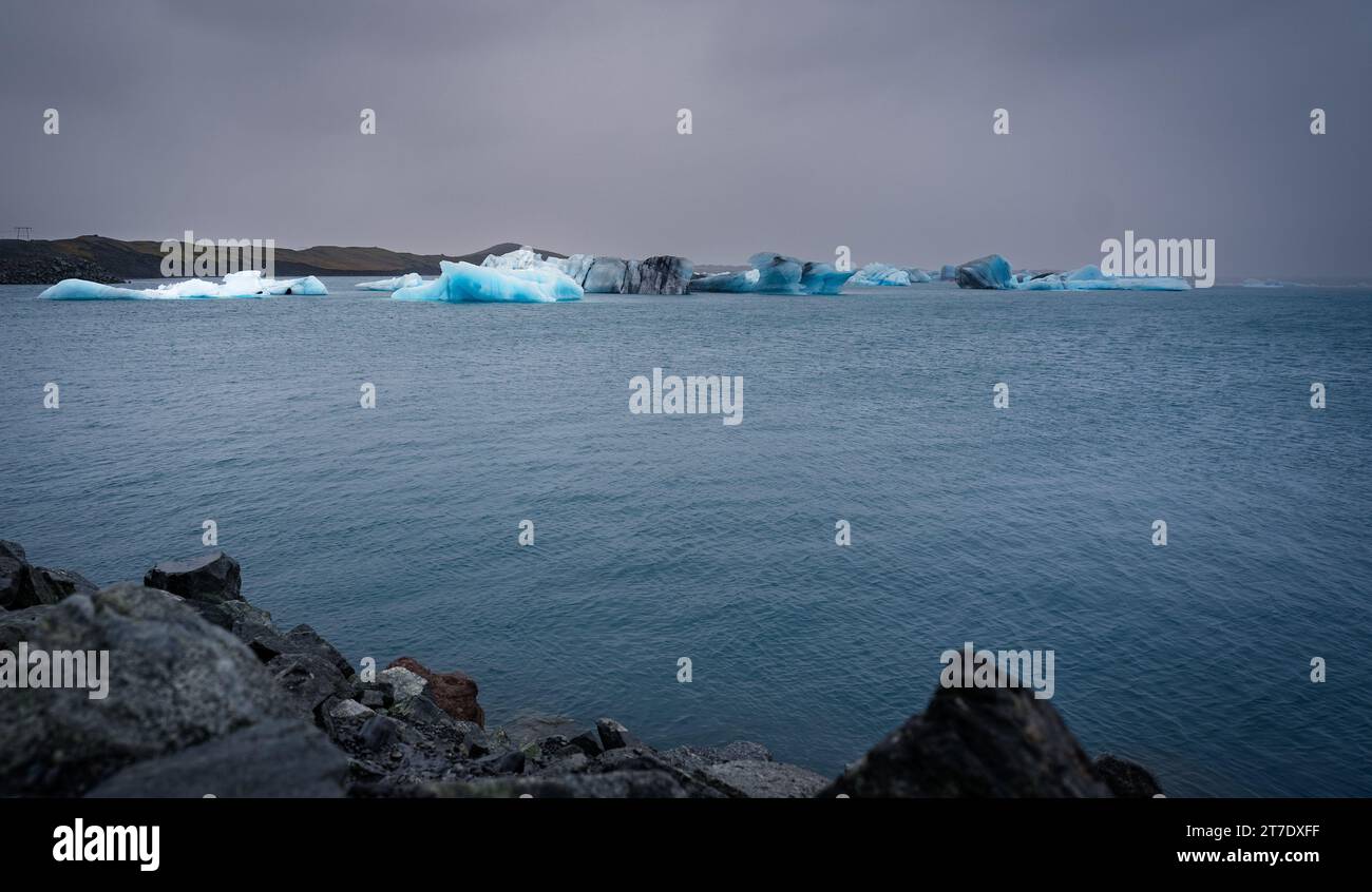 Multiple icebergs floating in a crystal-clear body of water near rocky ...