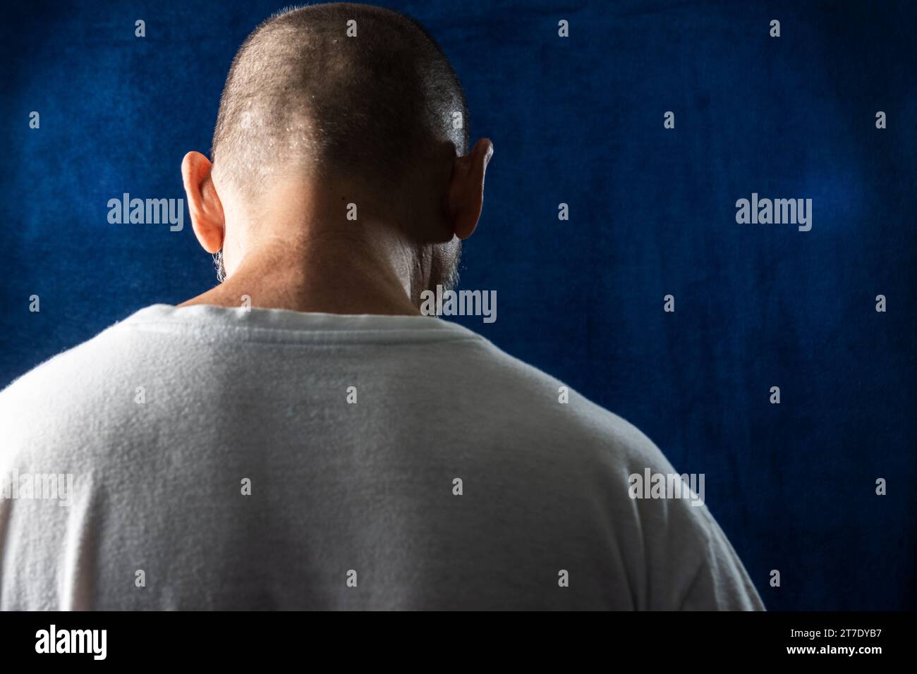 Man, with his back turned, sad, head down against blue background Stock ...