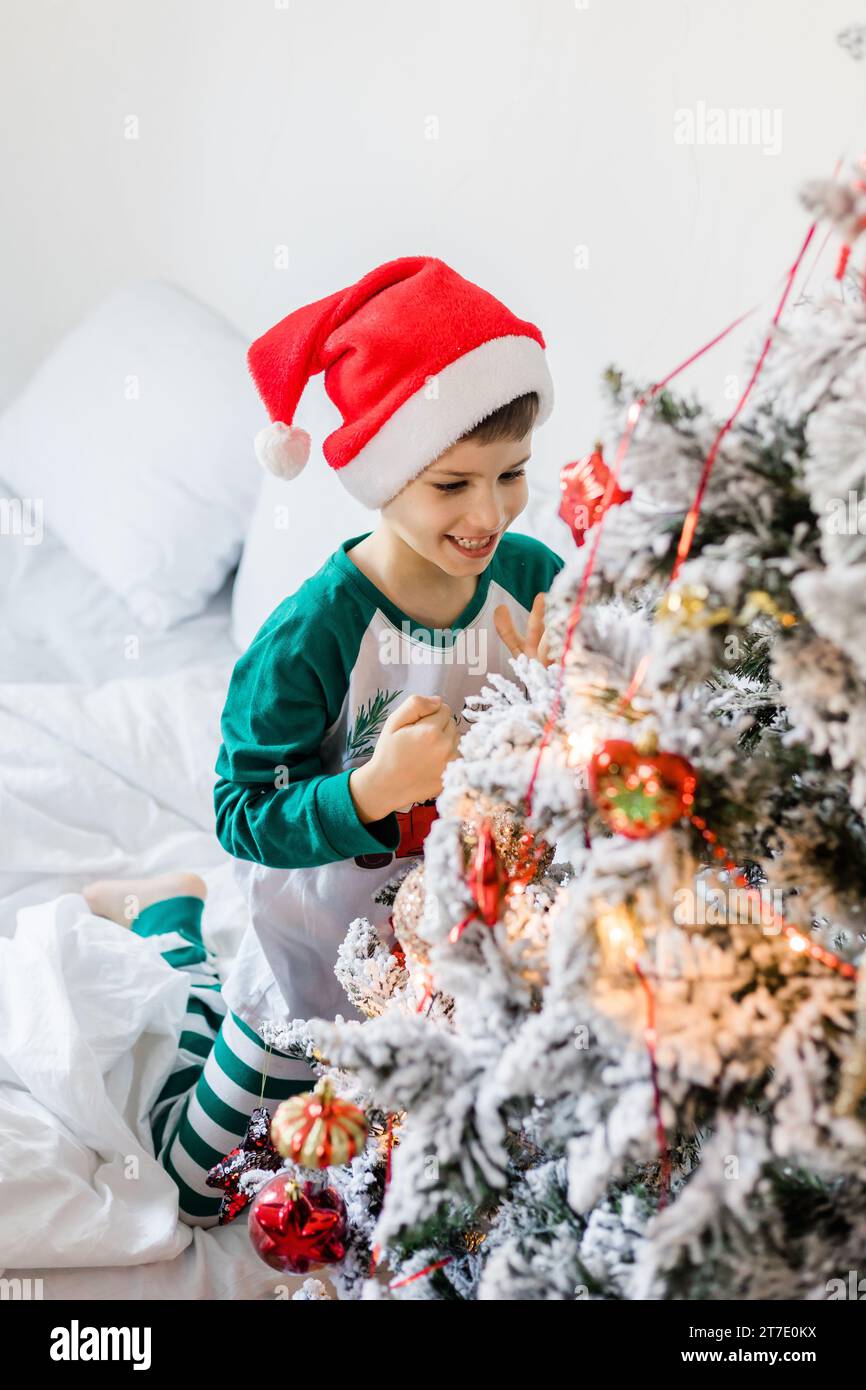 Close up of caucasian child hands putting ornaments on Christmas tree ...