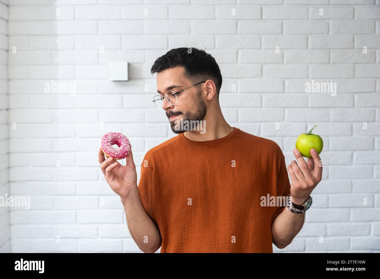Young student man doubts what to choose healthy food or sweets junk ...