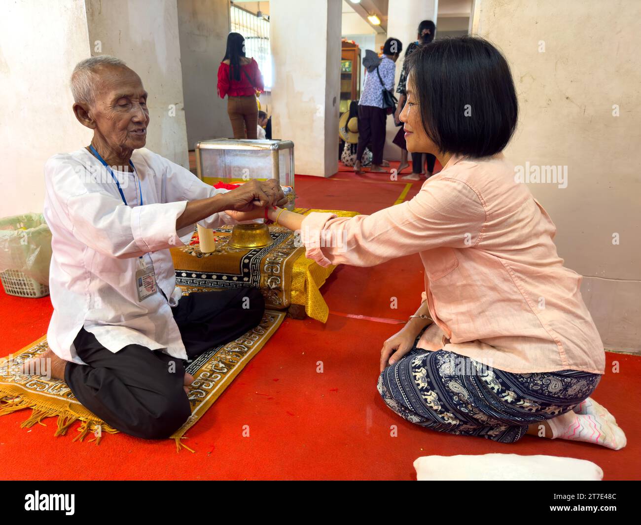 An elderly devout Buddhist lay person ties a sacred sangkhat, or cotton ...