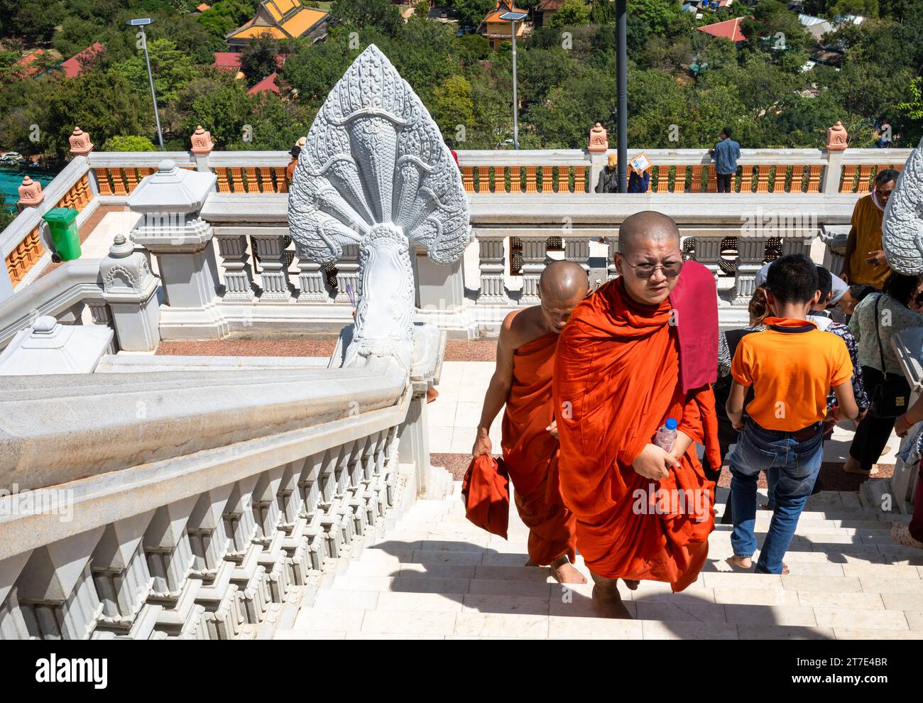 Two buddhist monks climb steps past visitors at Oudong Temple in Kandal ...