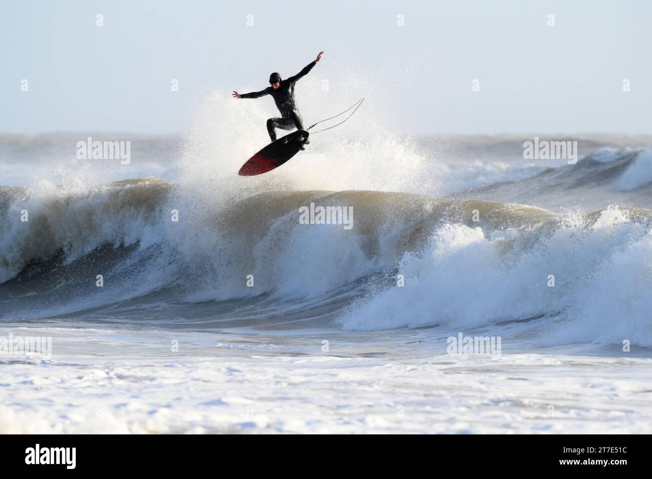 Surfing action on the Gower. Surfer highlighted in spray leaps clear of ...
