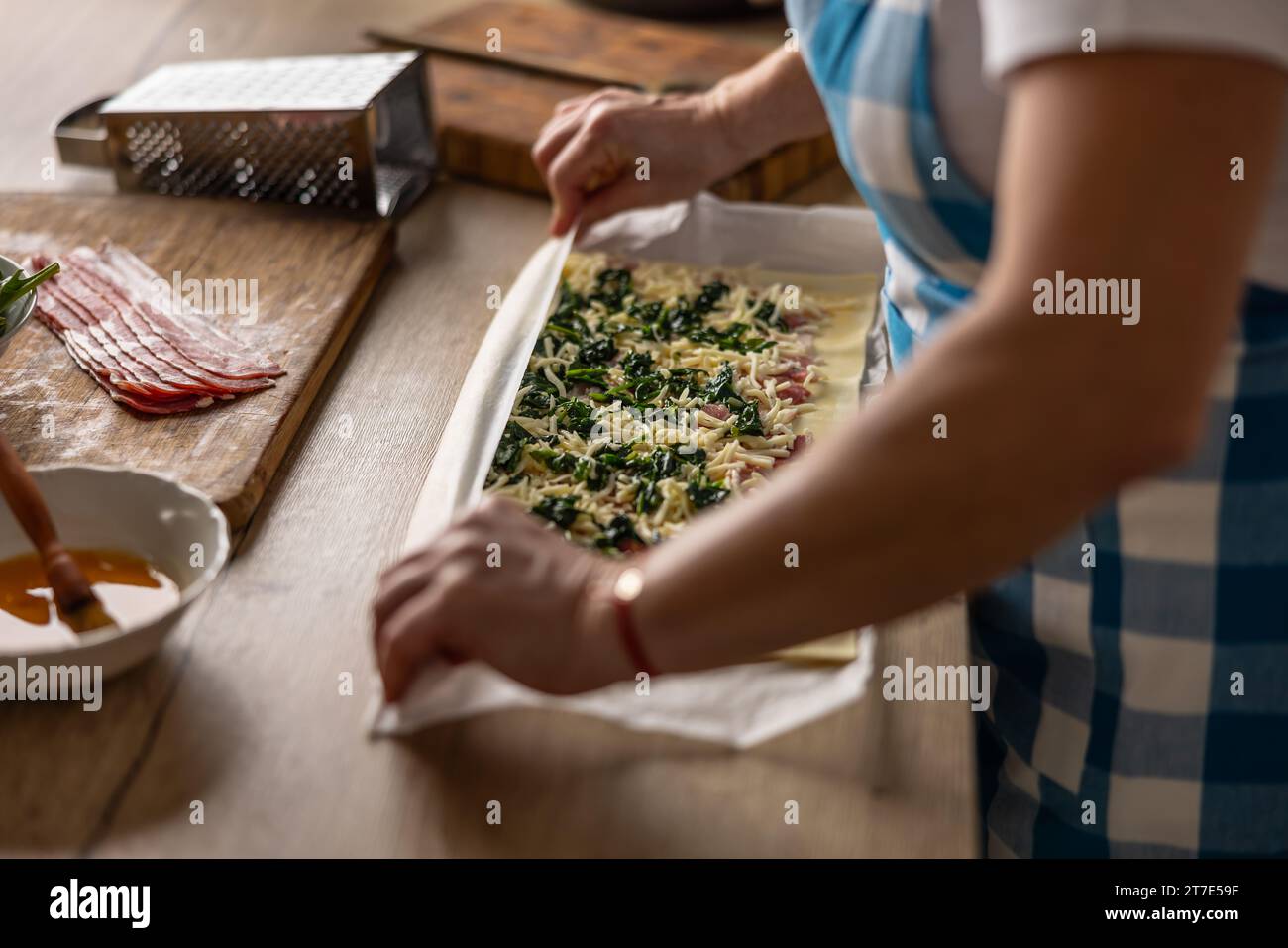 The cook rolls puff pastry with bacon, spinach and cheese, prepares ...