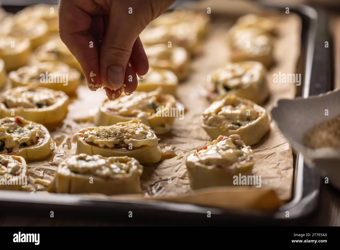 Female cooks hands sprinkle sesame on raw mini cakes before baking ...