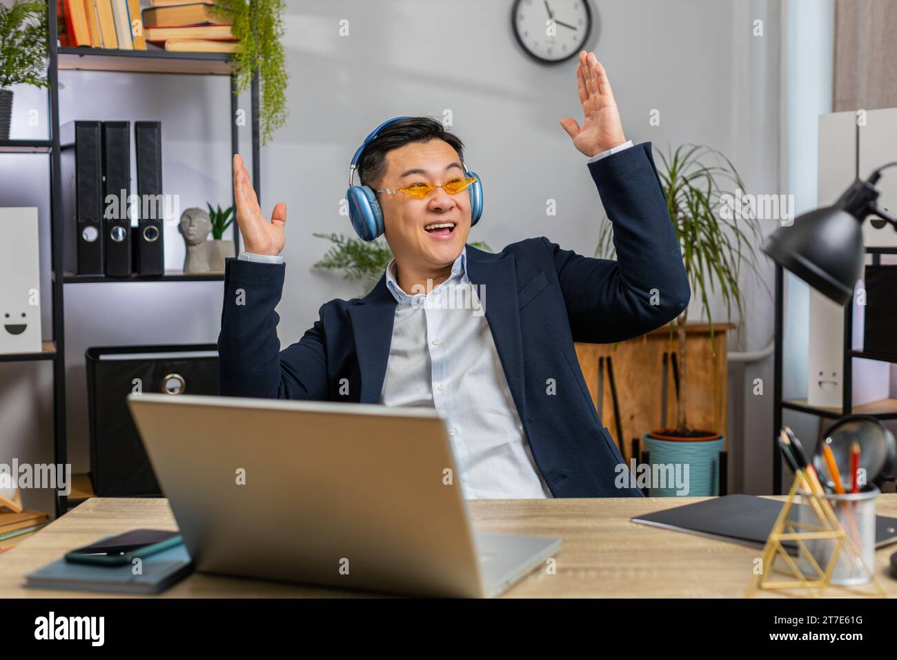 Happy relaxed Asian businessman in sunglasses working on laptop ...