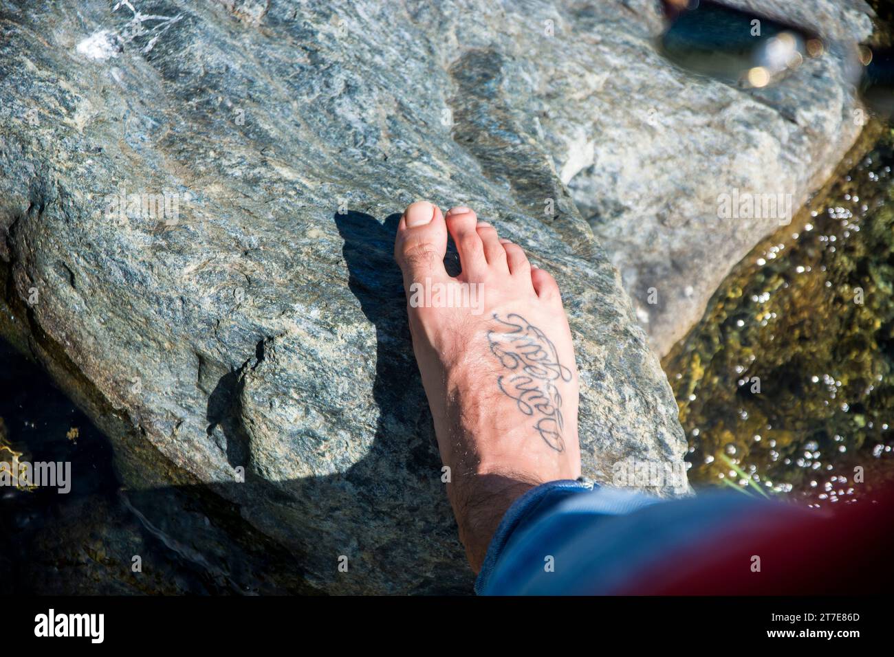 A person's foot on top of a rock next to a body of water Stock Photo ...
