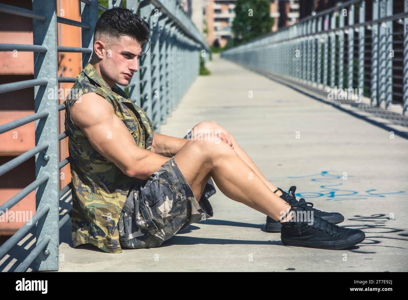 A man sitting on a bridge with his legs crossed Stock Photo - Alamy