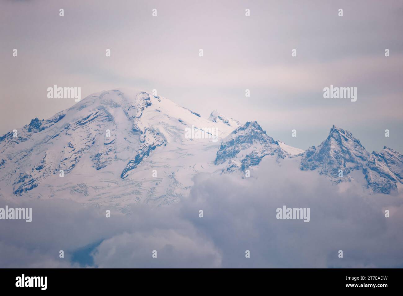 A majestic landscape of snow-covered Mount Baker peaks and cloudy skies ...
