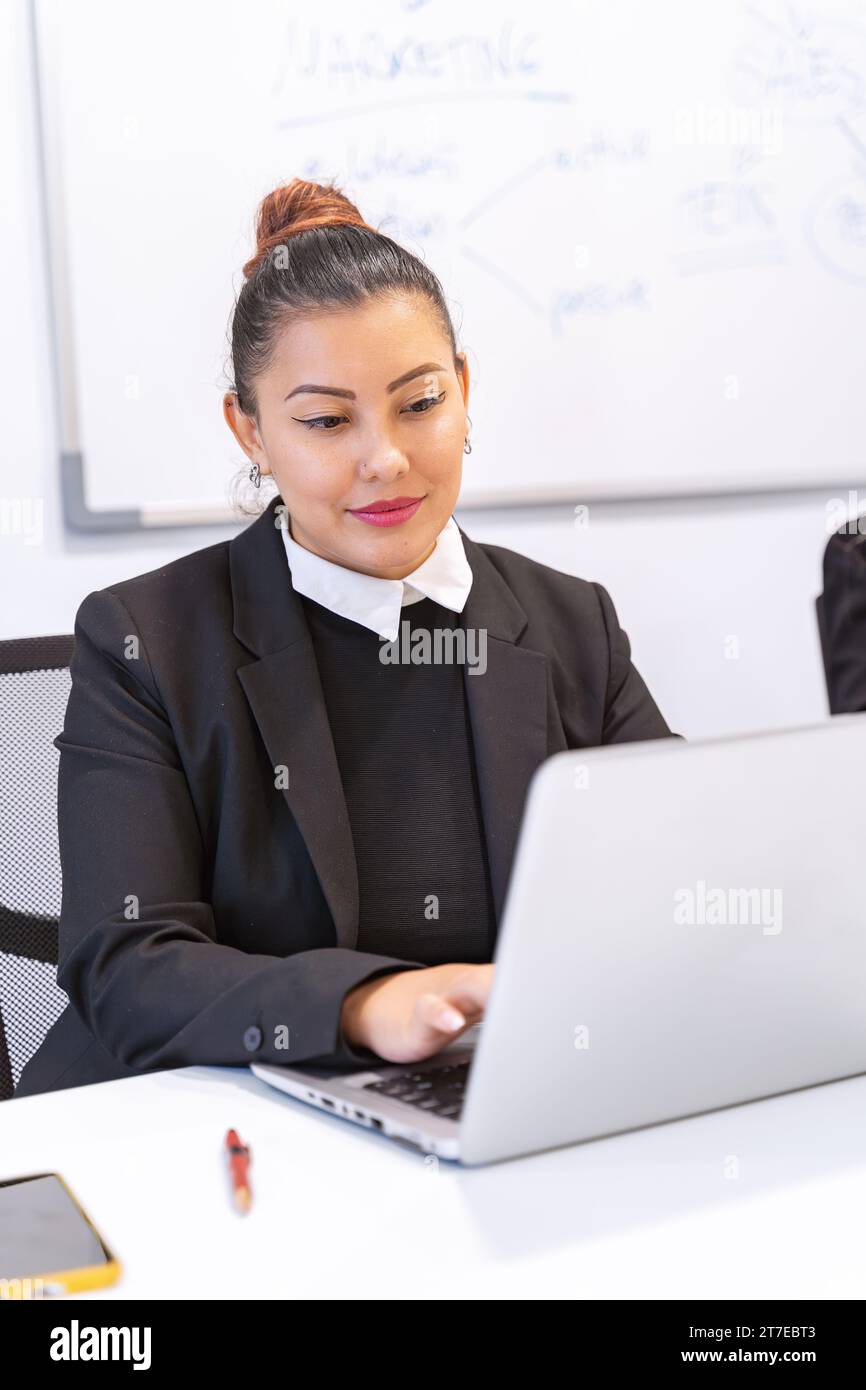 A focused Latina woman immersed in her office work, showcasing ...
