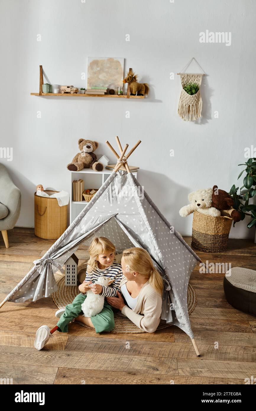 disabled girl with prosthetic leg holding toy rabbit near happy mother ...