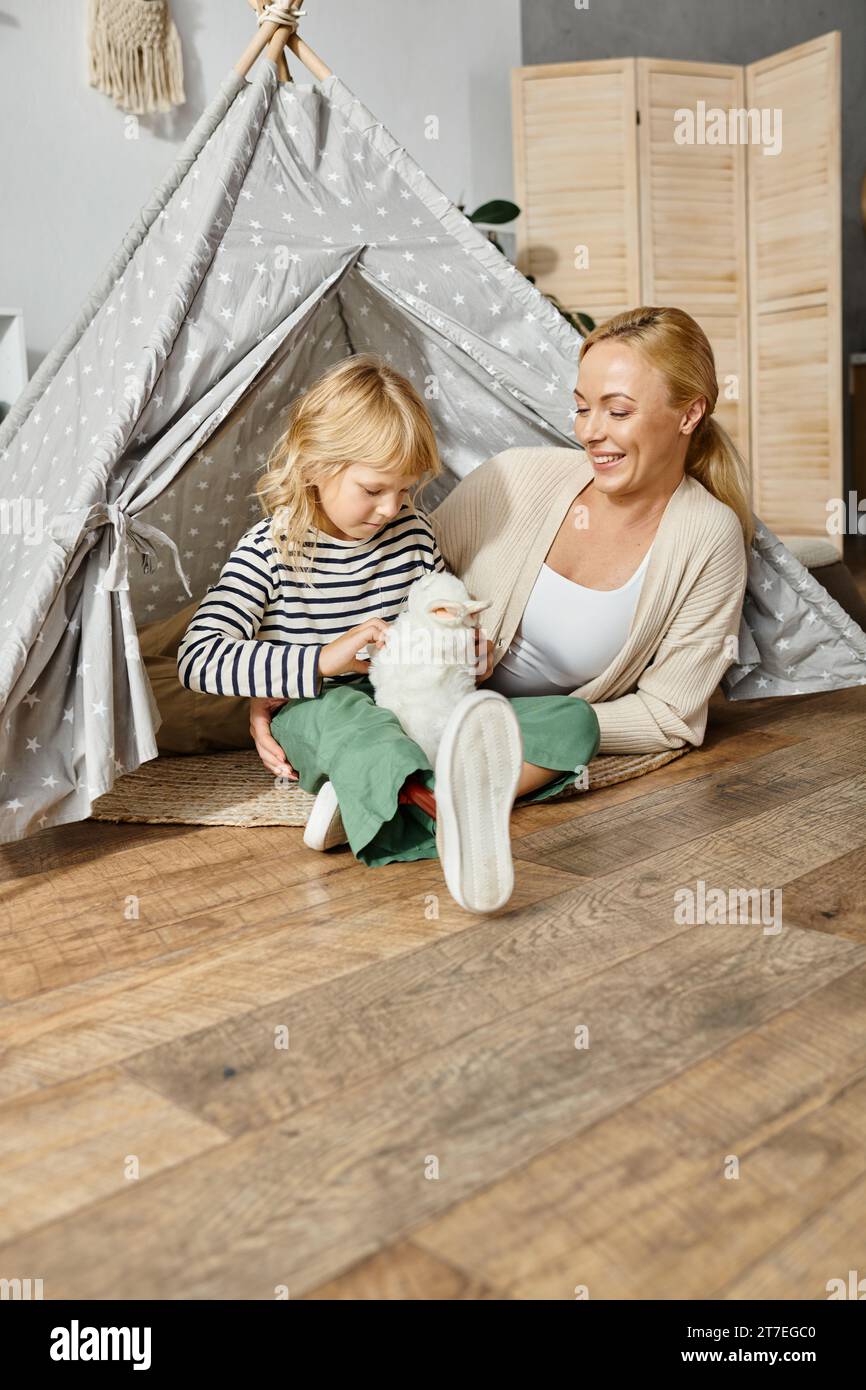 blonde girl with prosthetic leg playing with soft toy rabbit near ...