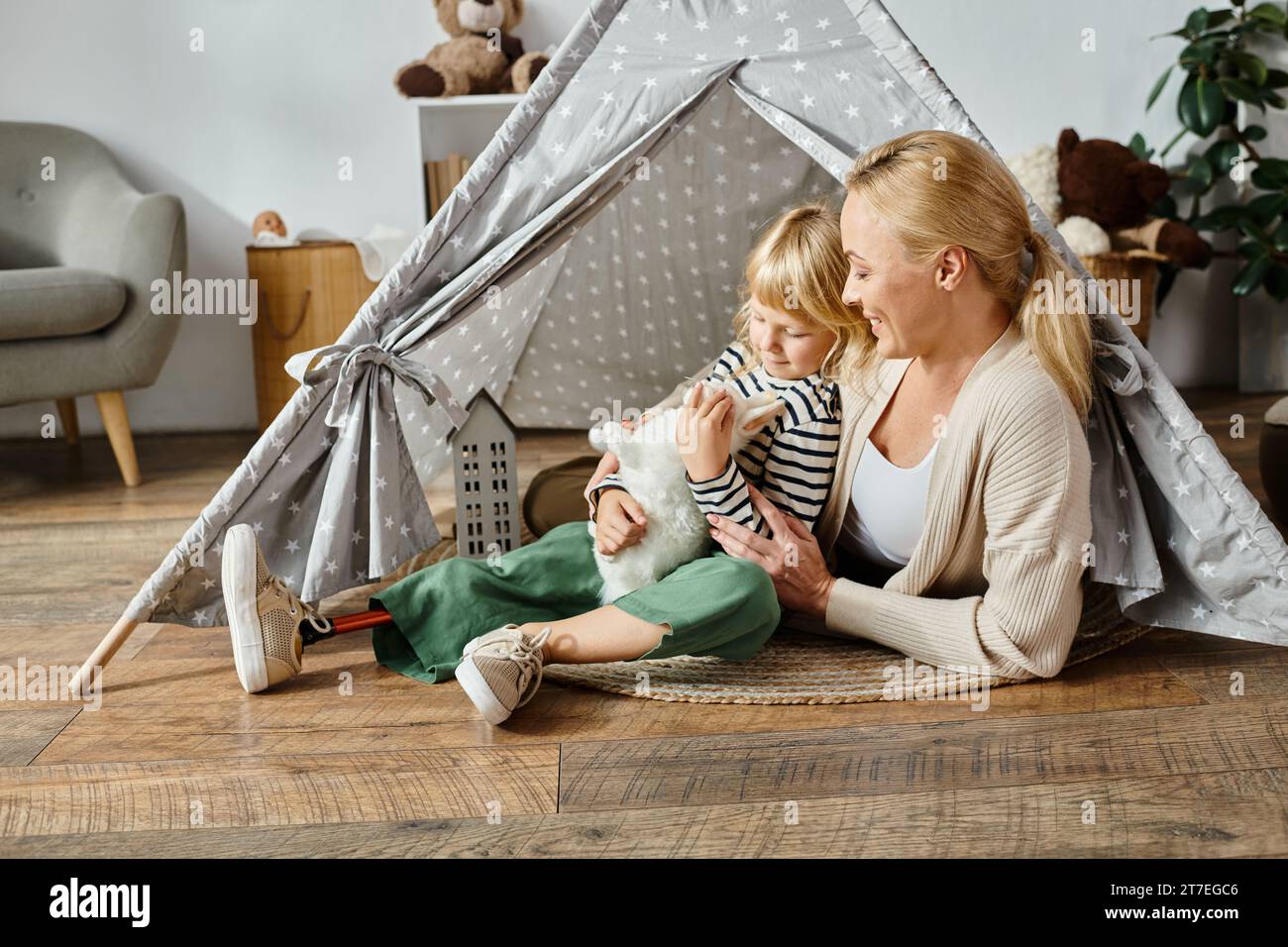 little girl with prosthetic leg hugging soft toy rabbit near happy ...
