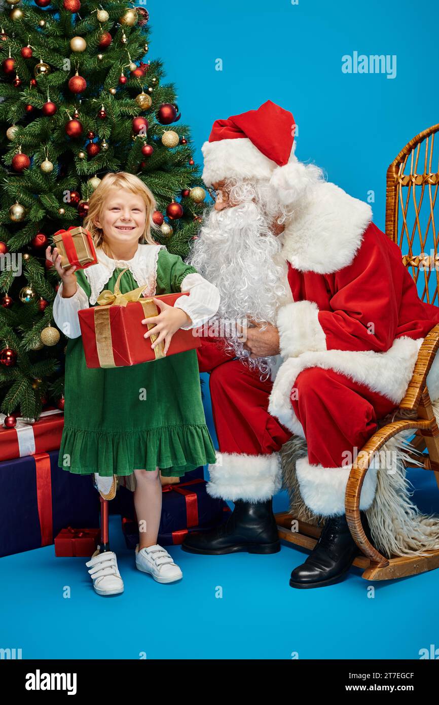 Santa Claus giving presents to happy girl with prosthetic leg next to ...