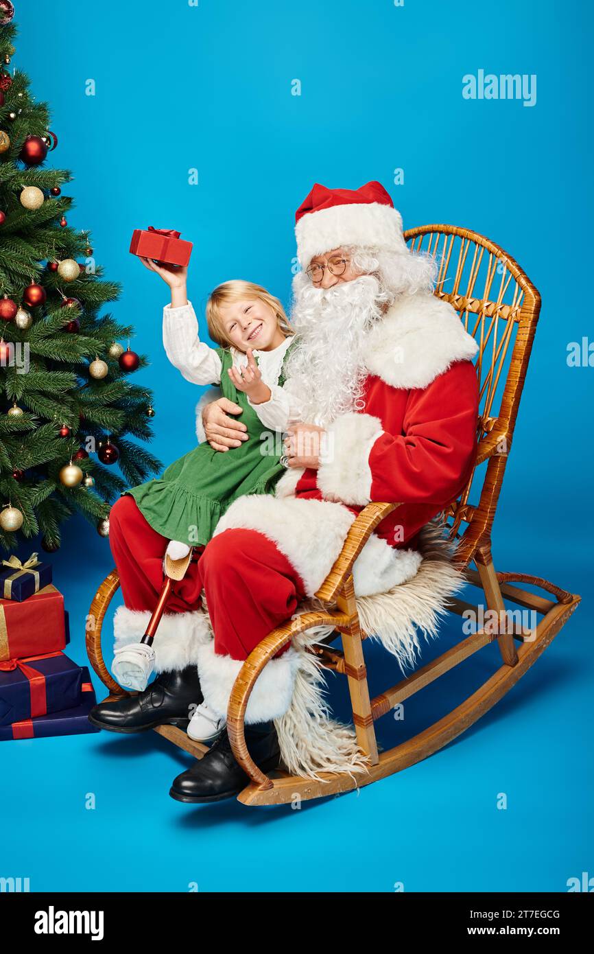 happy girl with prosthetic leg sitting on laps of Santa Claus with gift ...