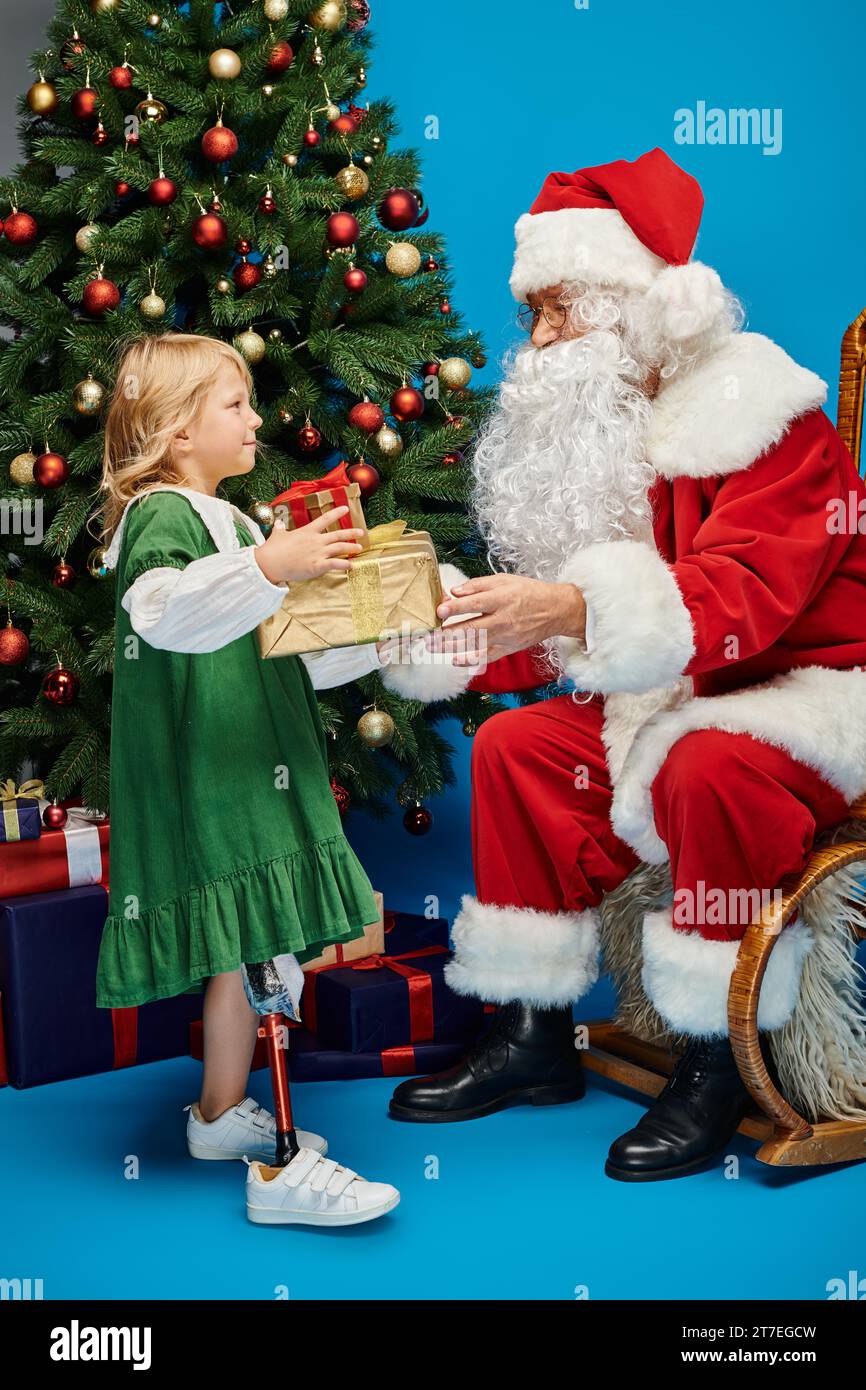 Santa Claus giving presents to happy girl with prosthetic leg next to ...