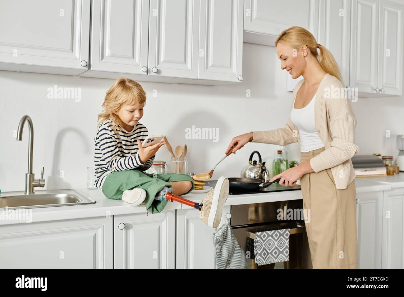 happy girl with prosthetic leg sitting on countertop with smartphone ...