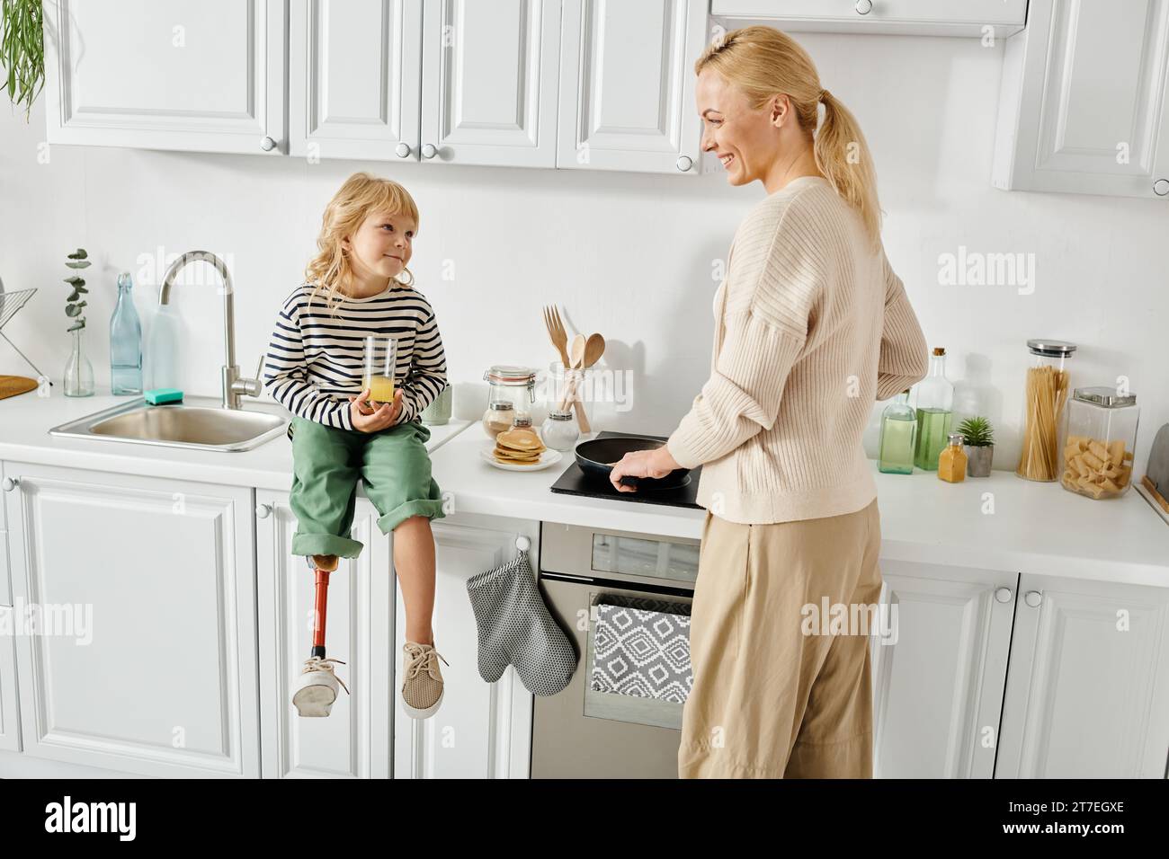 happy girl with prosthetic leg sitting on countertop with orange juice ...