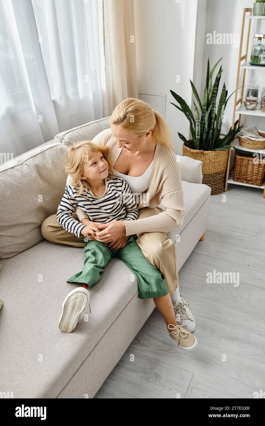 blonde mother hugging happy kid with prosthetic leg and sitting ...