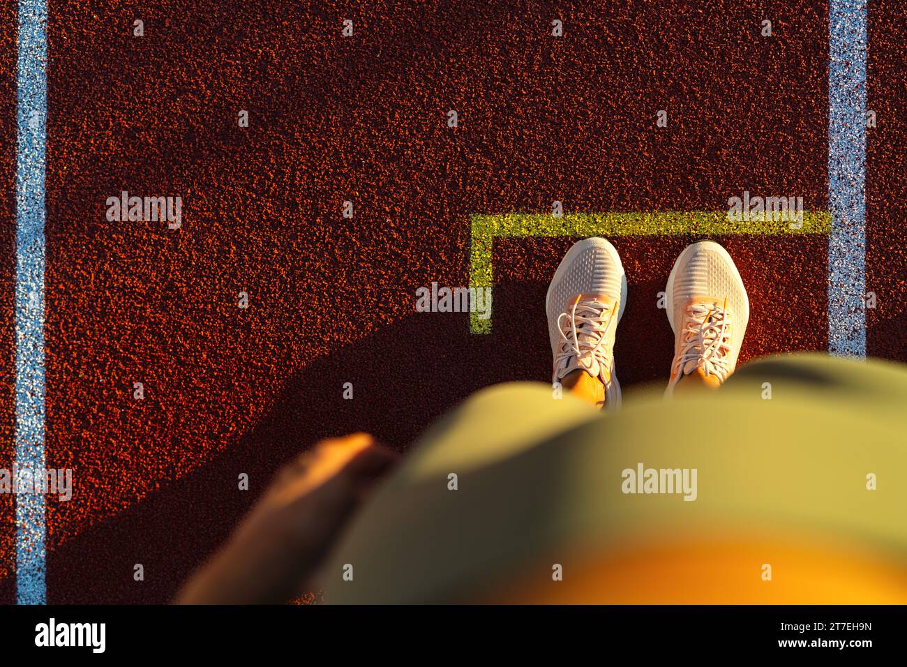 Top-down view of a person's feet at the start line on a running track ...